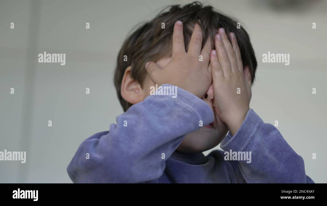 Shy child covering eyes with hands. Close up cute small boy hiding face ...