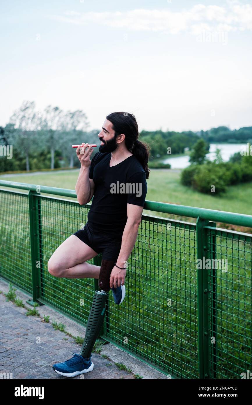Man with prosthetic leg sending an audio note after exercising outdoors ...
