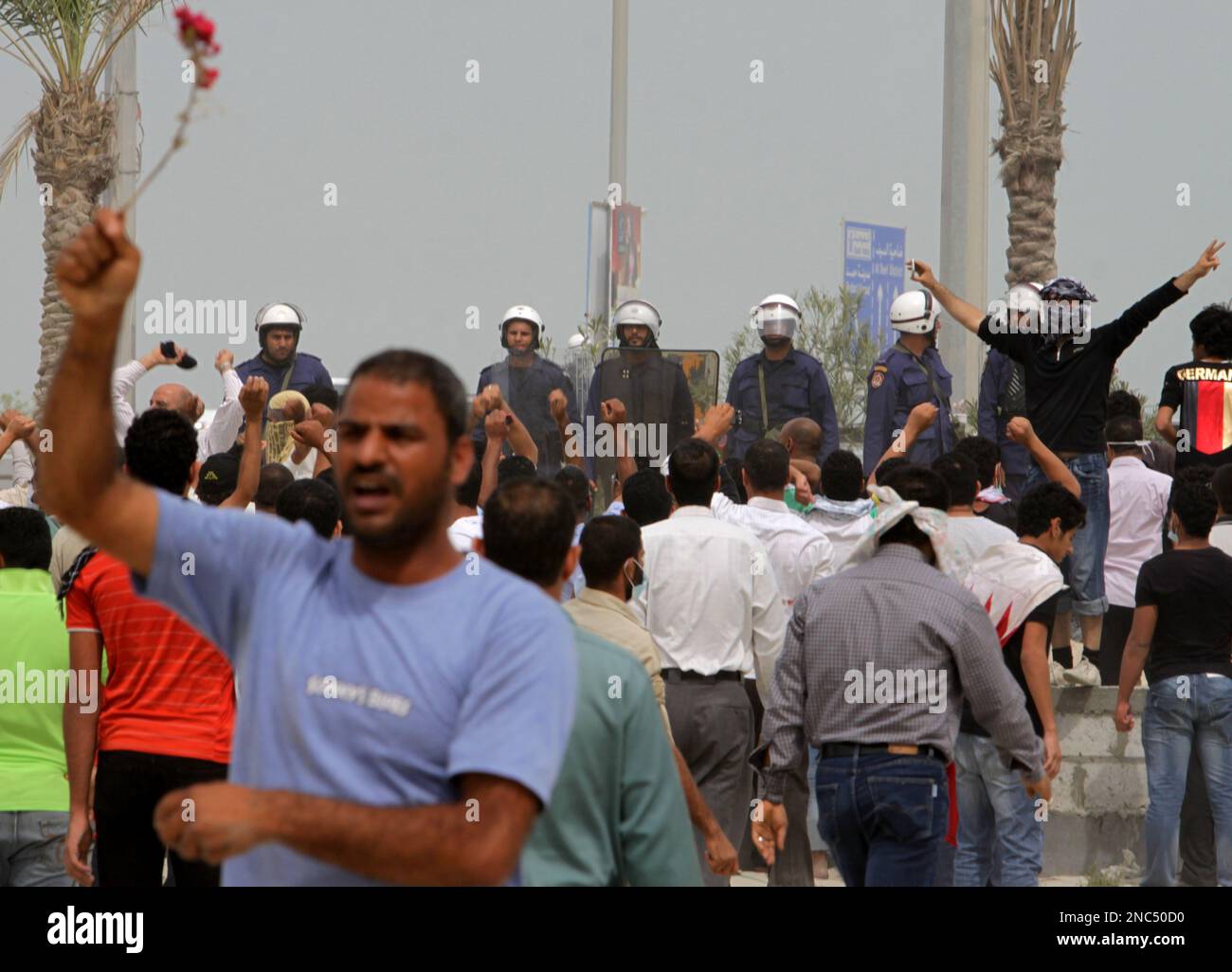 Anti-government protesters chant and wave flowers in front of riot ...
