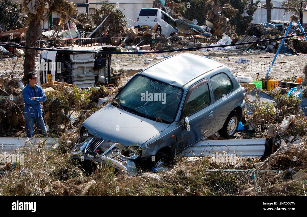 A survivor looks at a damaged car lying on a pedestrian's rail after ...