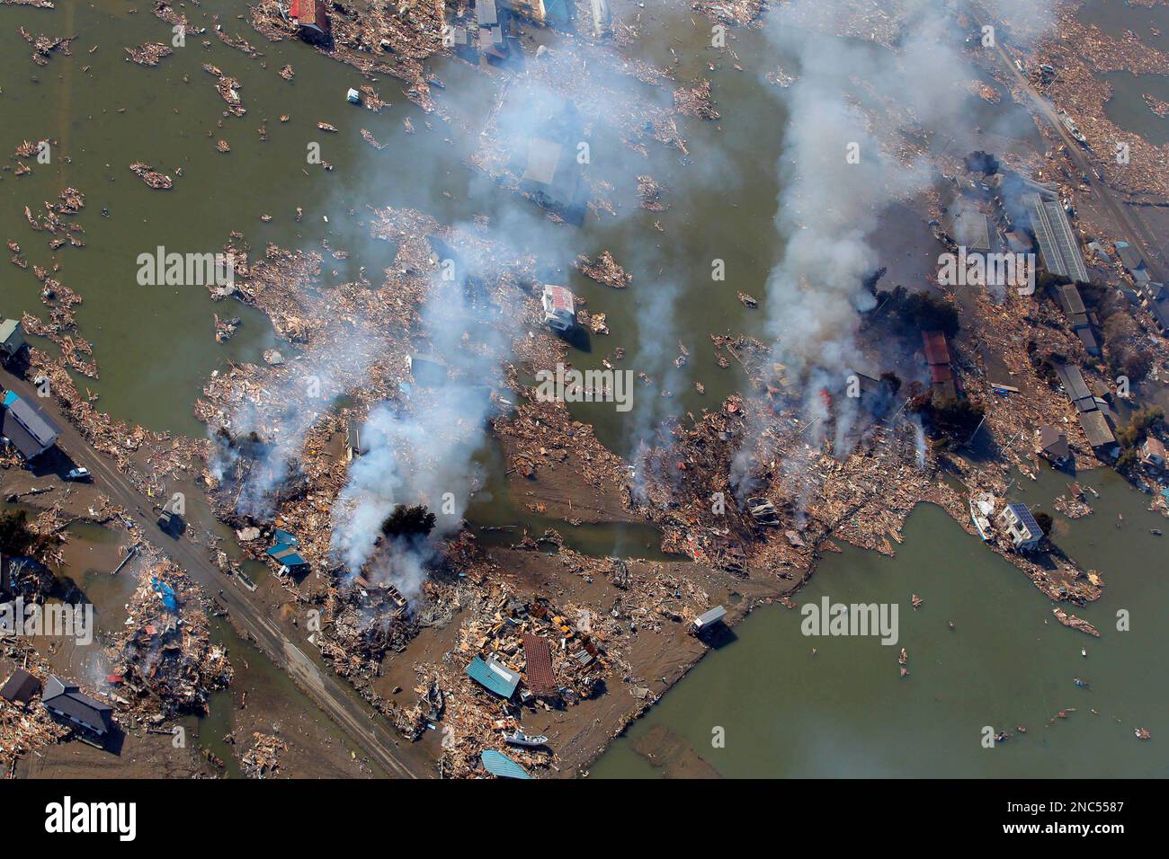 Smoke rises over an area in flood in Sendai, northern Japan, Saturday ...