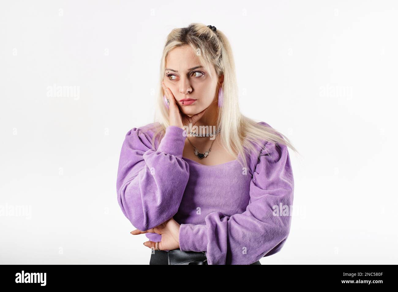 Portrait of young blonde woman wearing ribbed blouse standing isolated ...