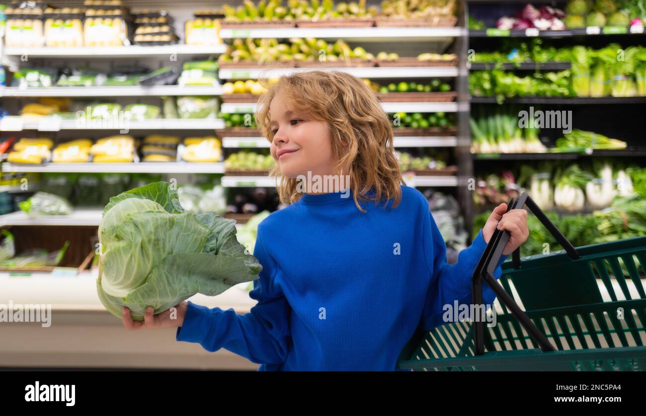 Child with cabbage. Kid in a food store or a supermarket. Little kid ...
