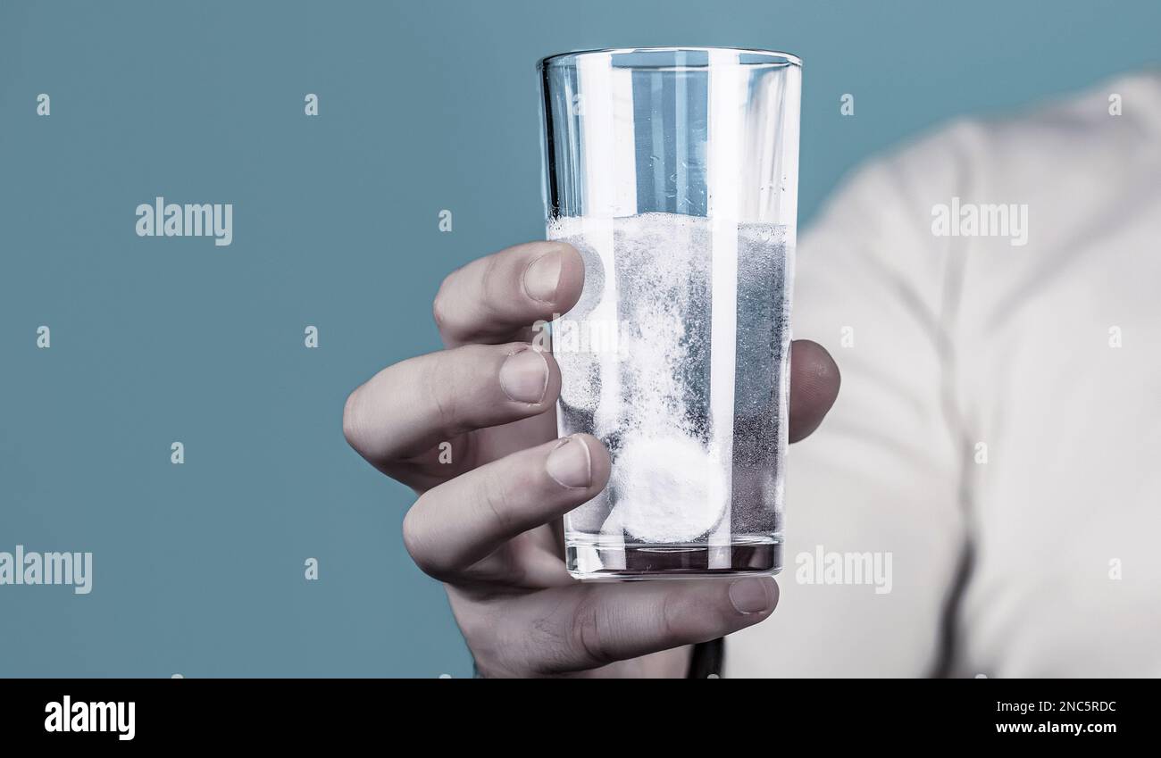 White pill and a glass of water in man hands. Glass of water tablet ...