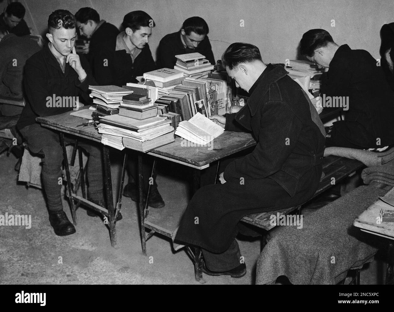 A group of “student teachers” sit at a book-piled table to study ...