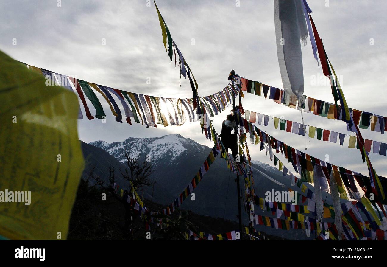An exile Tibetan ties multi-color flags on a high pole during the third ...
