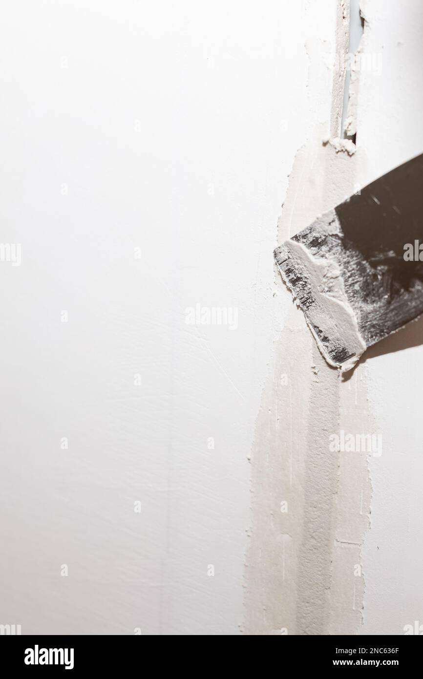 Worker fixing cracks on ceiling, spreading plaster using trowel ...