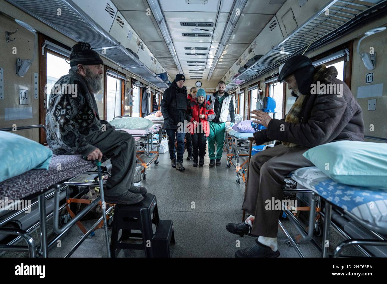 Medic and rescue serviceman help en elderly woman to take her seat ...