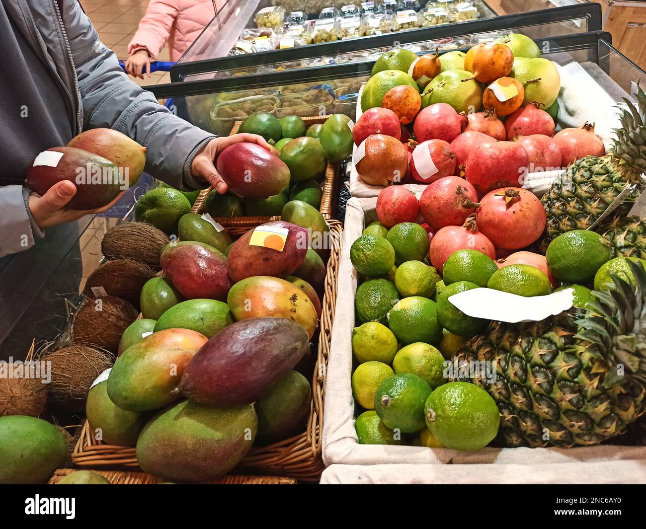 Close-up customer holding ripe organic mango, standing by a counter ...