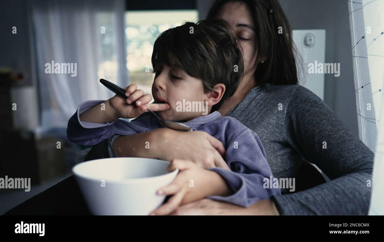 Small boy sitting on mother lap in morning. Child wearing pajamas ...