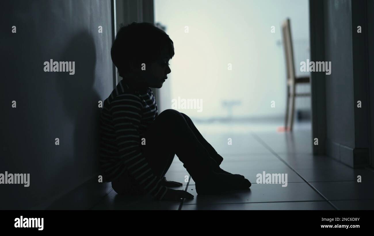 Sad child suffering from depression sitting alone in corridor feeling ...