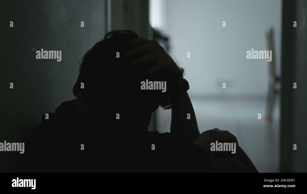 Sad unhappy man sitting on floor holding his forehead while having ...