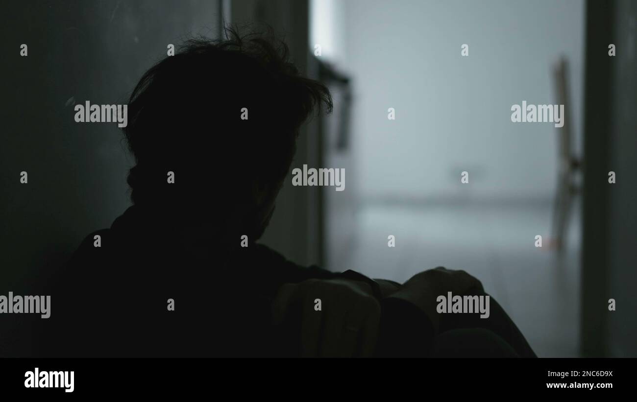 Sad unhappy man sitting on floor holding his forehead while having ...