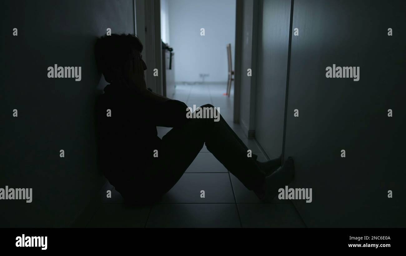 Depressed man sitting on floor. Sad unhappy person holding his forehead ...