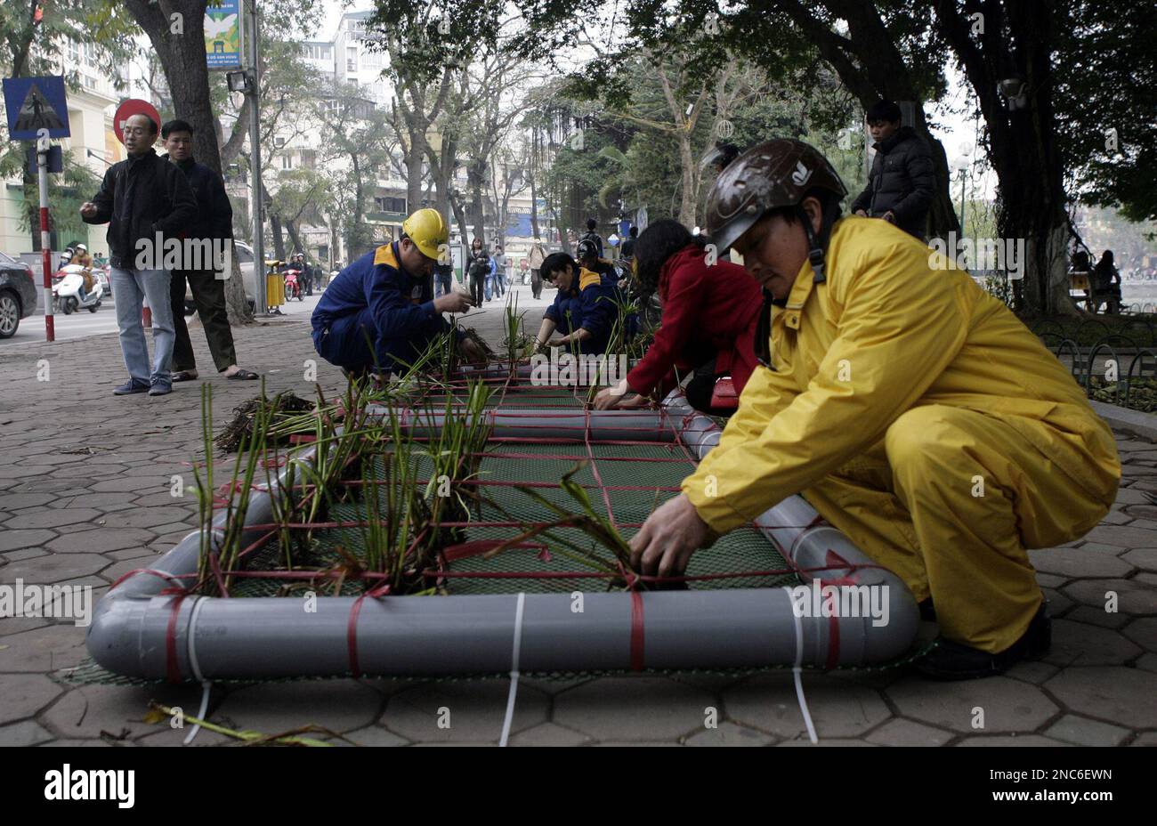 Workers prepare a floating raft with plants that will be placed into ...