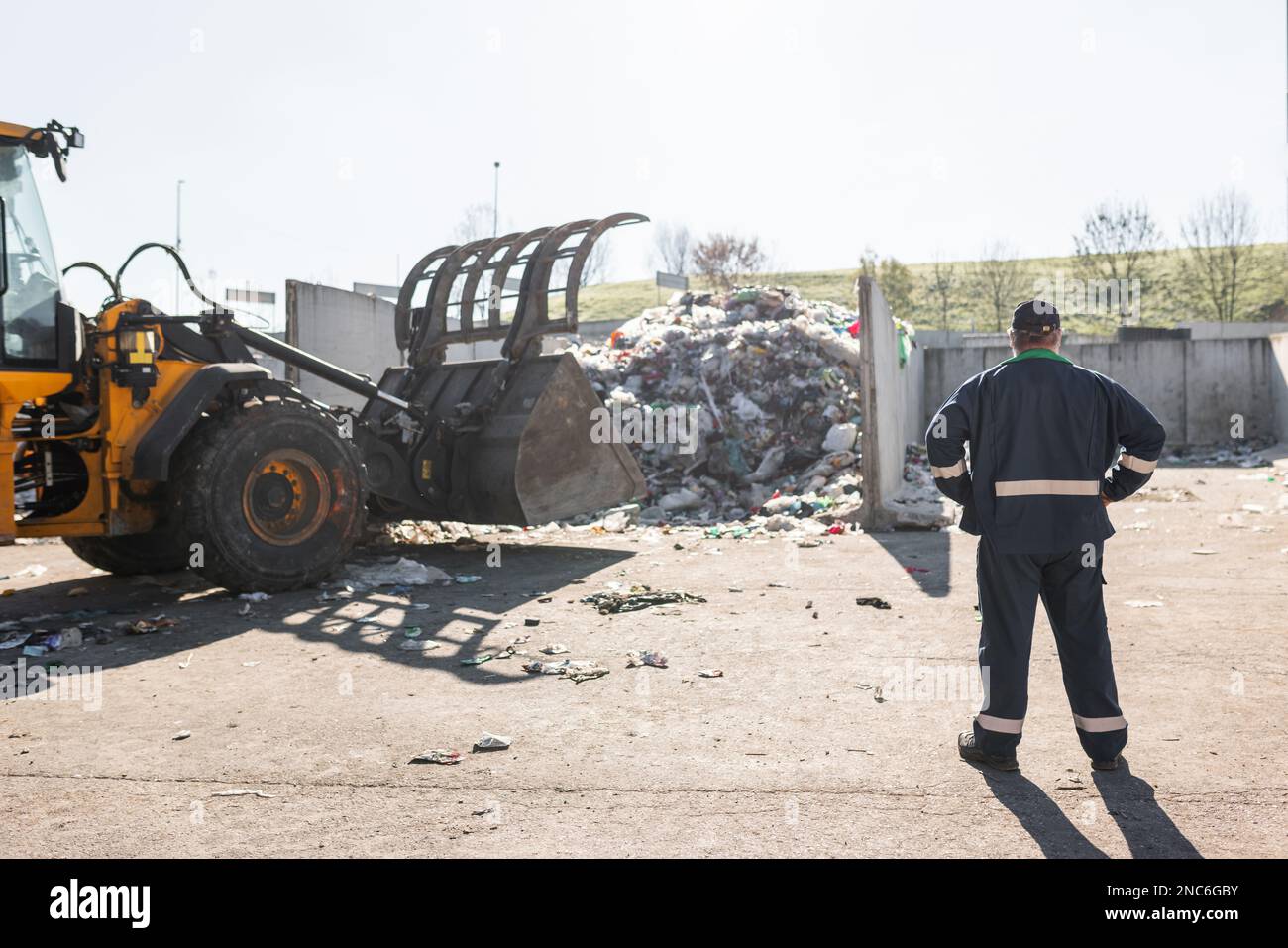 Recycling center worker, in dark blue work clothes, looking at an ...