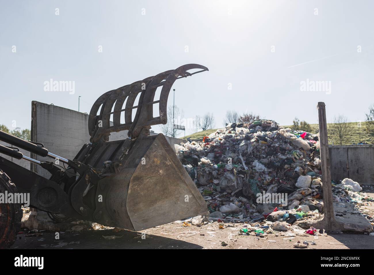 Yellow skid steer loader moving wooden waste material, shaking out a ...