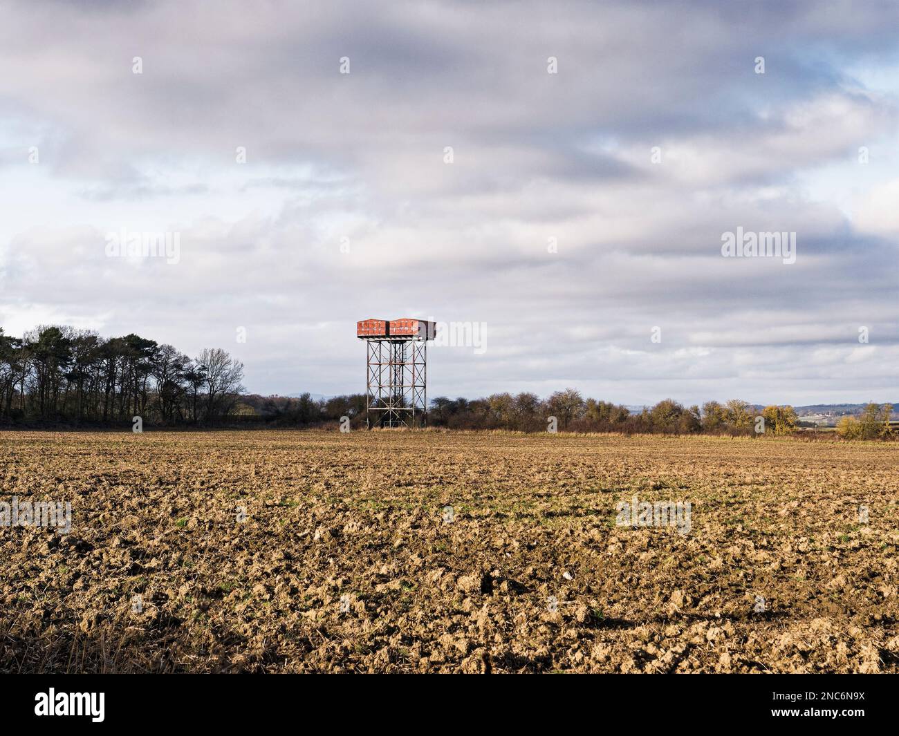 Arable landscape, ploughed field, with disused water tower and copy ...