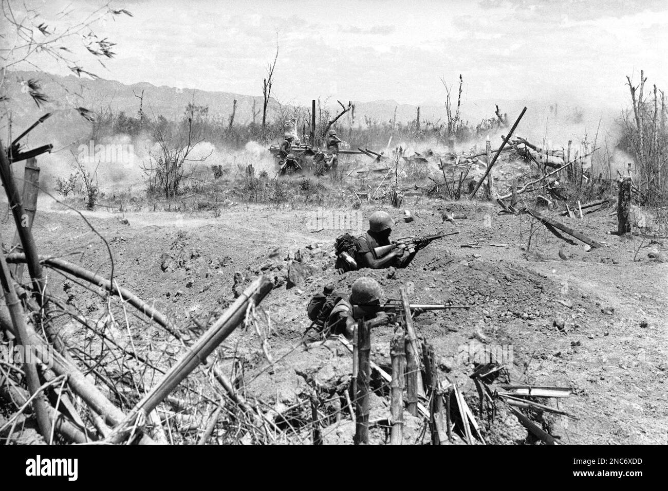Two marines exchange fire with Viet Cong in bunkers while a 106mm ...