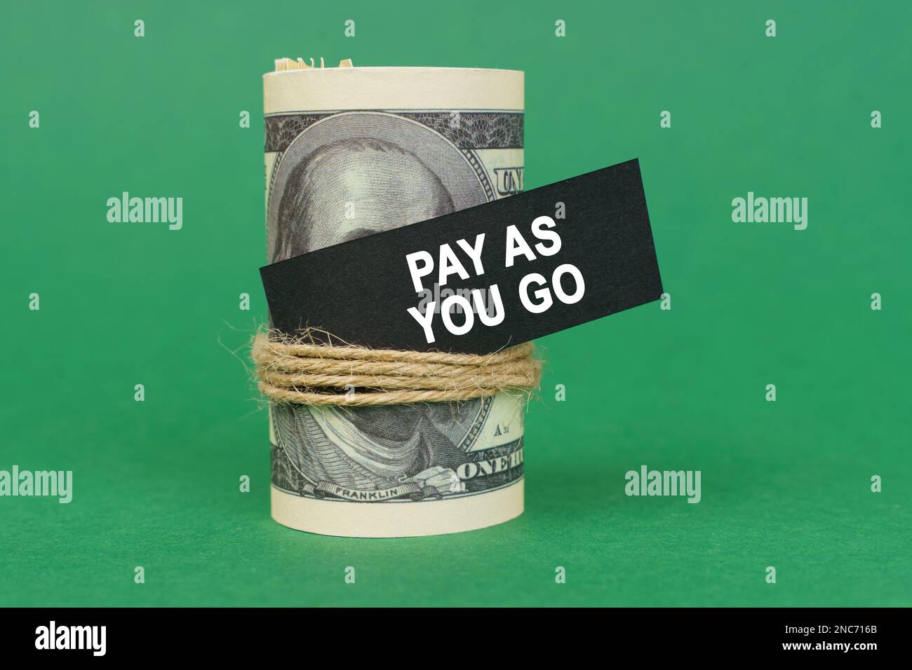 Business concept. On a green surface, rolled dollars with a black sign ...