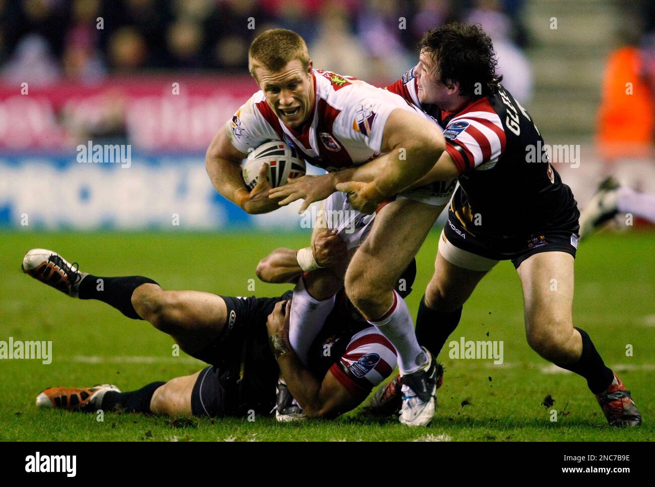 St. George Illawarra Dragons' Ben Creagh, center, is tackled by Wigan ...