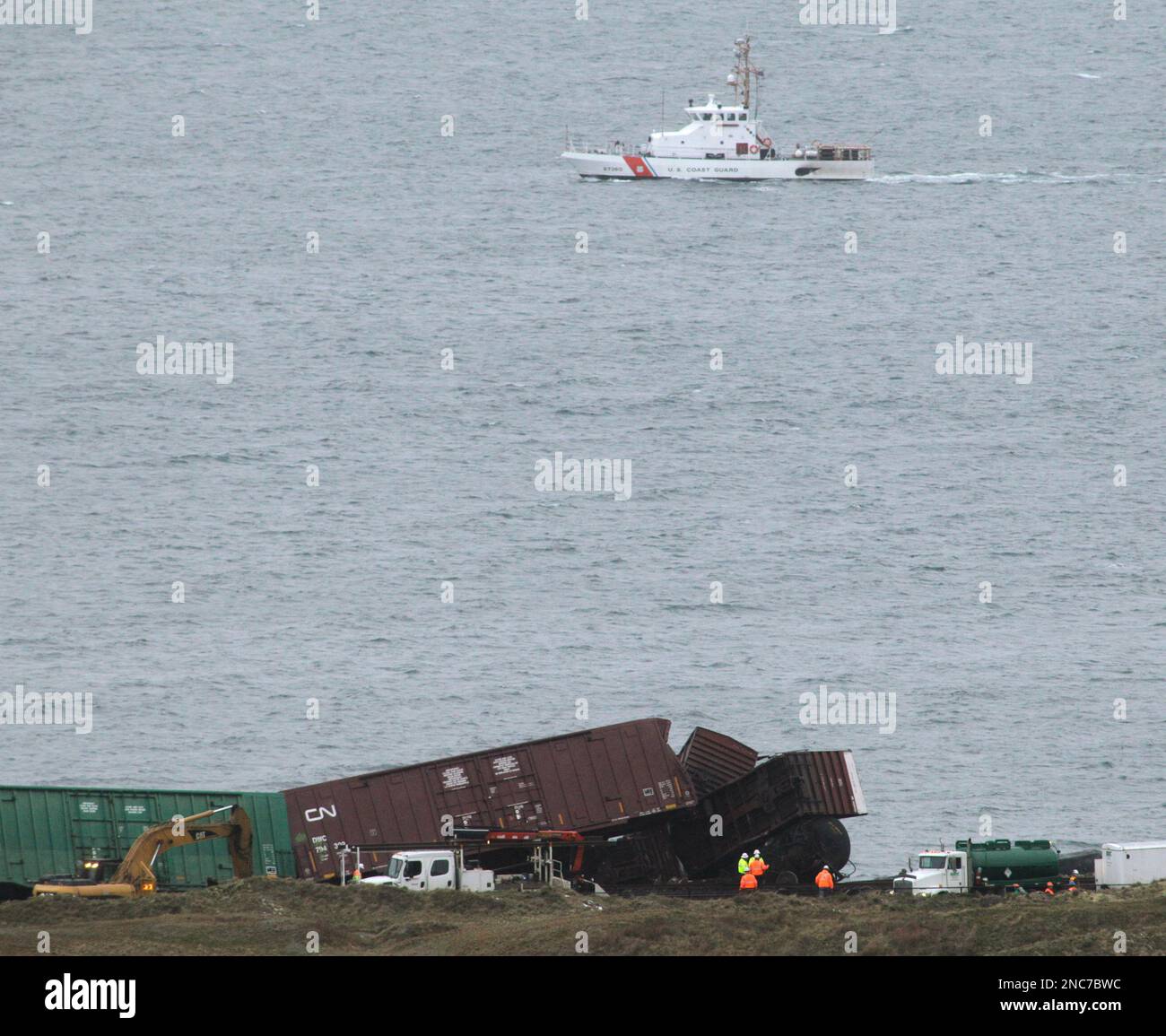 A U.S. Coast Guard boat passes several derailed train cars, including a ...