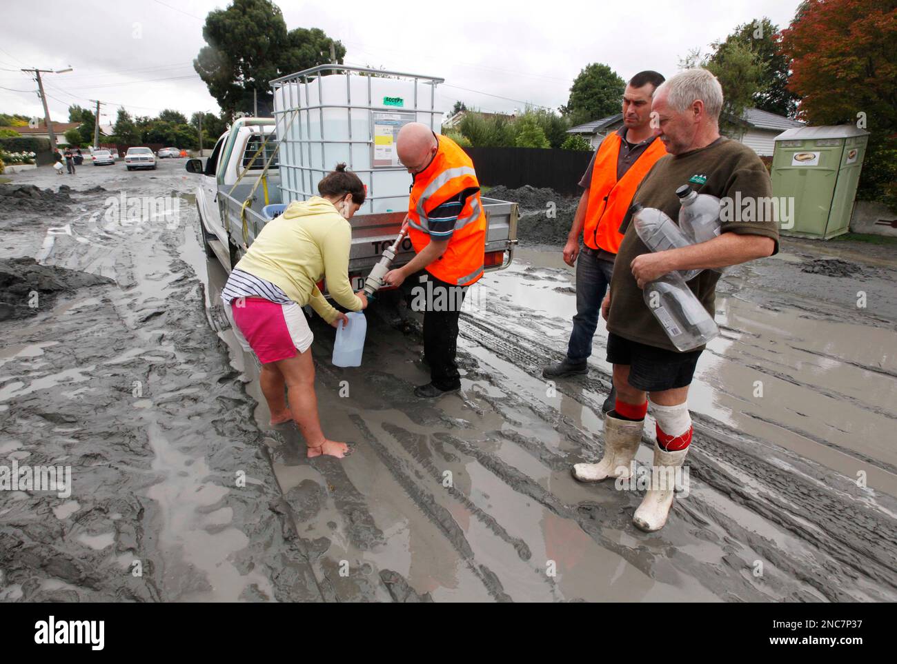 A resident fills her water container while another waits in their ...