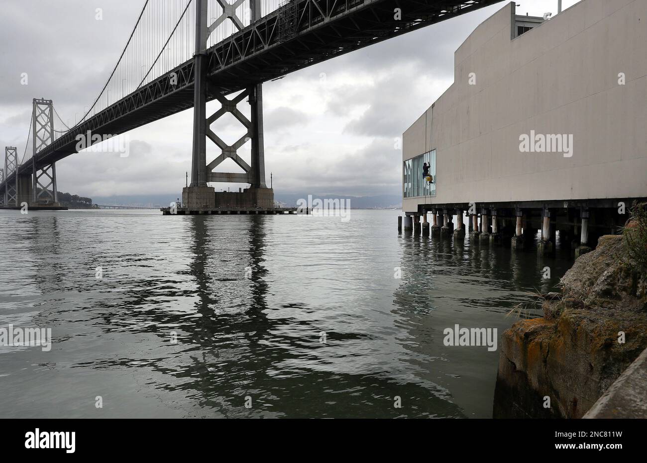 Wooden pilings support waterfront buildings as a window washer hangs ...