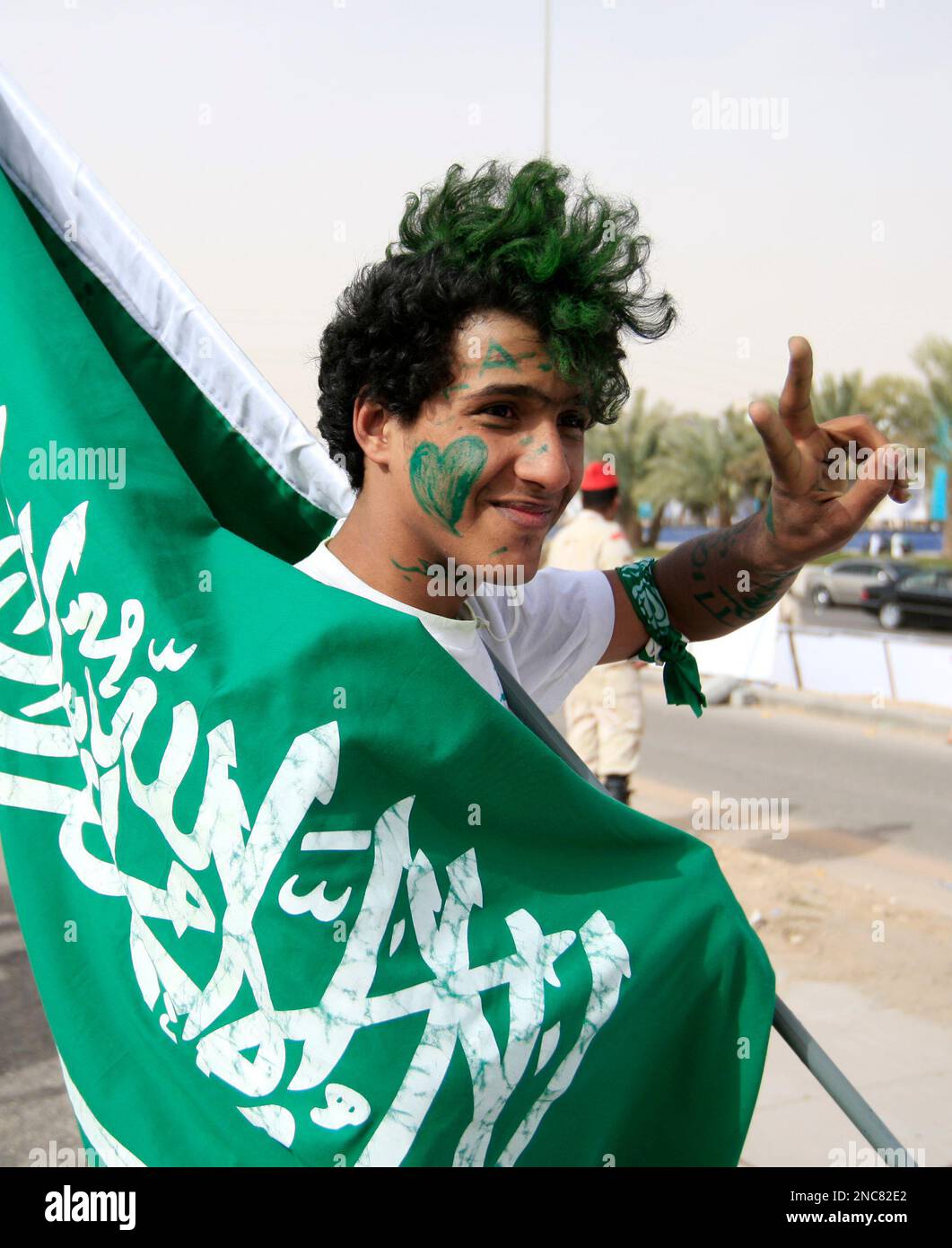 A Saudi wrapped by the Saudi national flag flashes the victory sign as ...