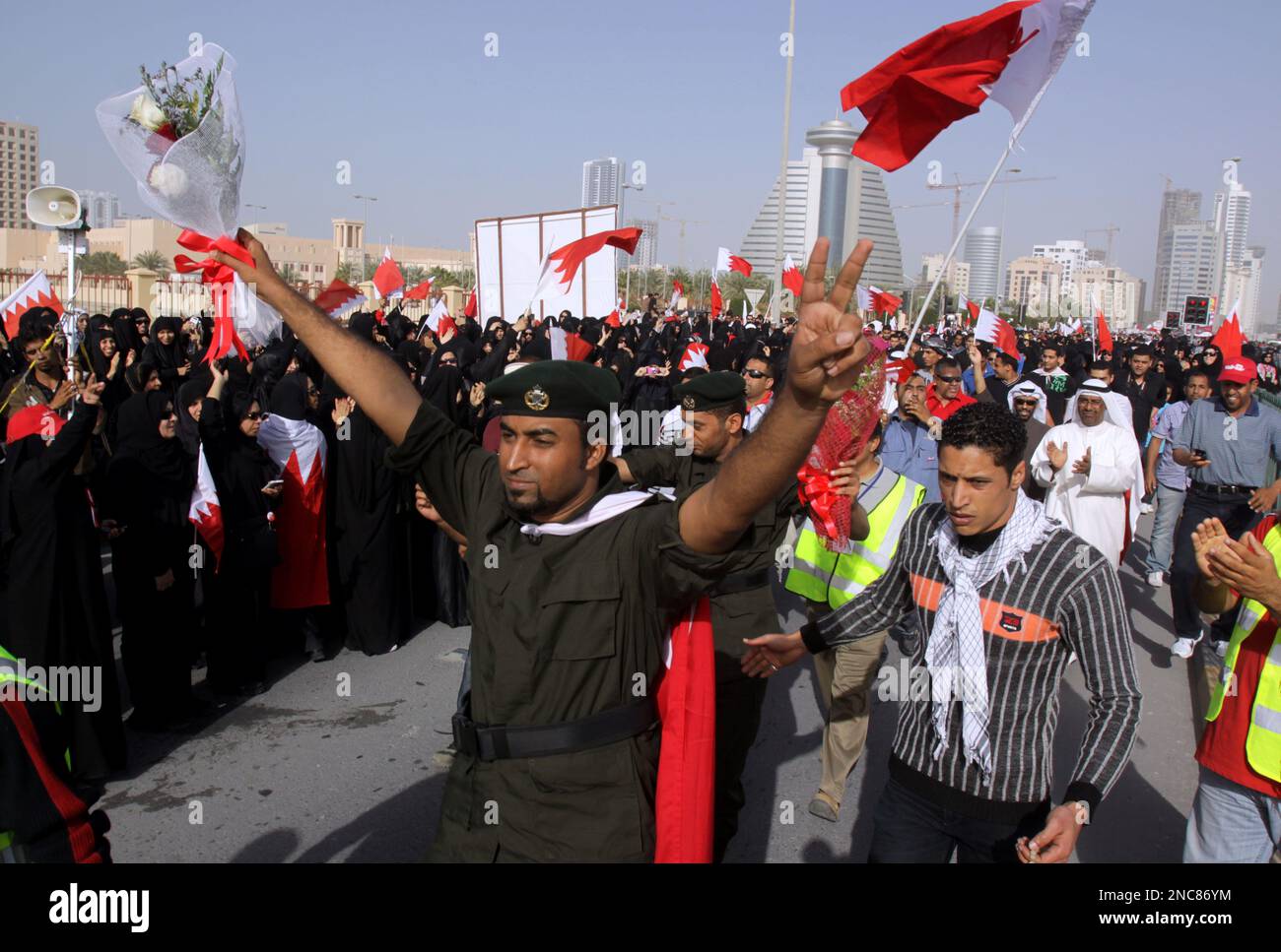 Bahraini police officers hold up flowers as they walk in solidarity ...