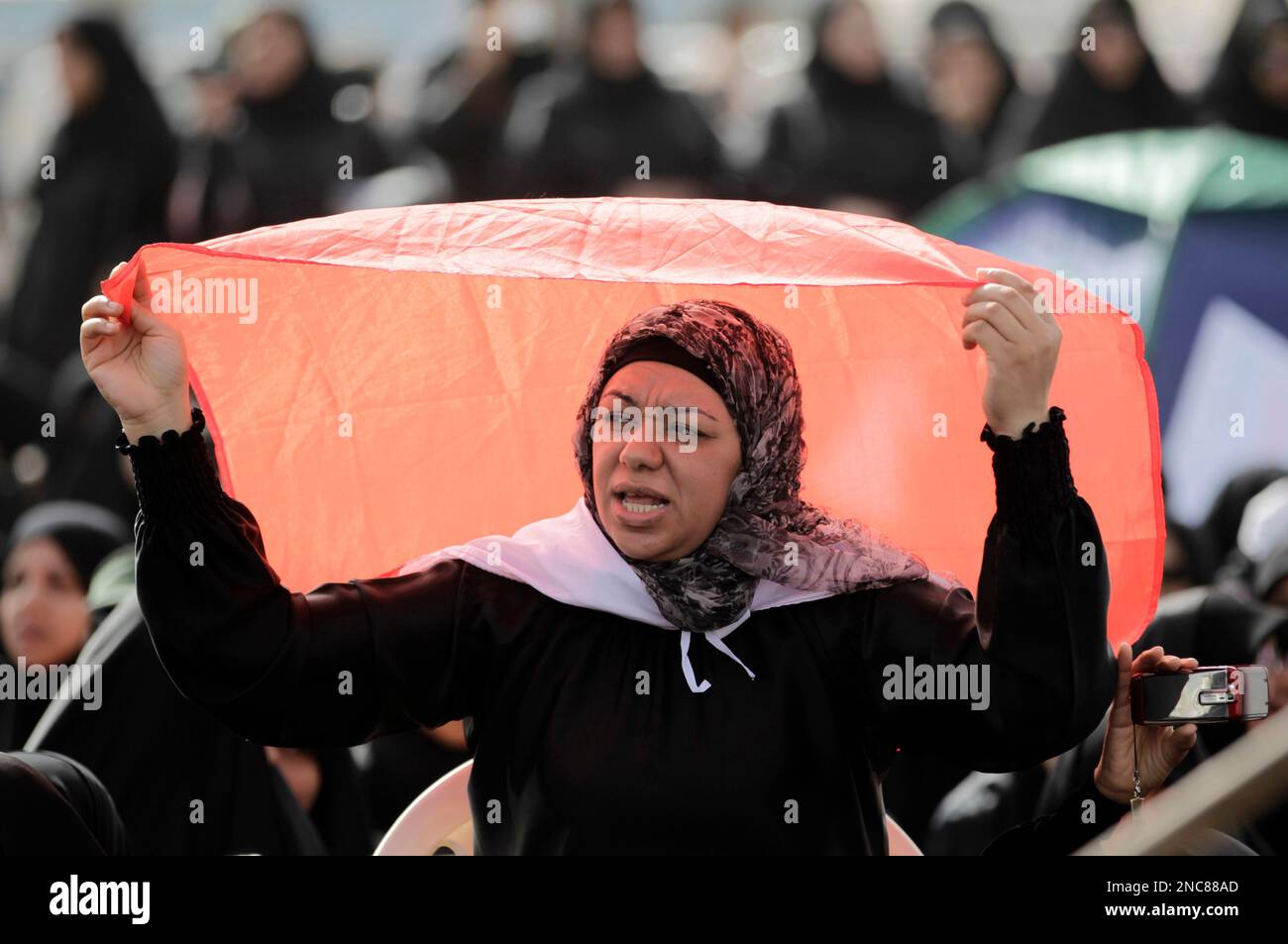 A Bahraini anti-government protester shouts slogans as she covers ...