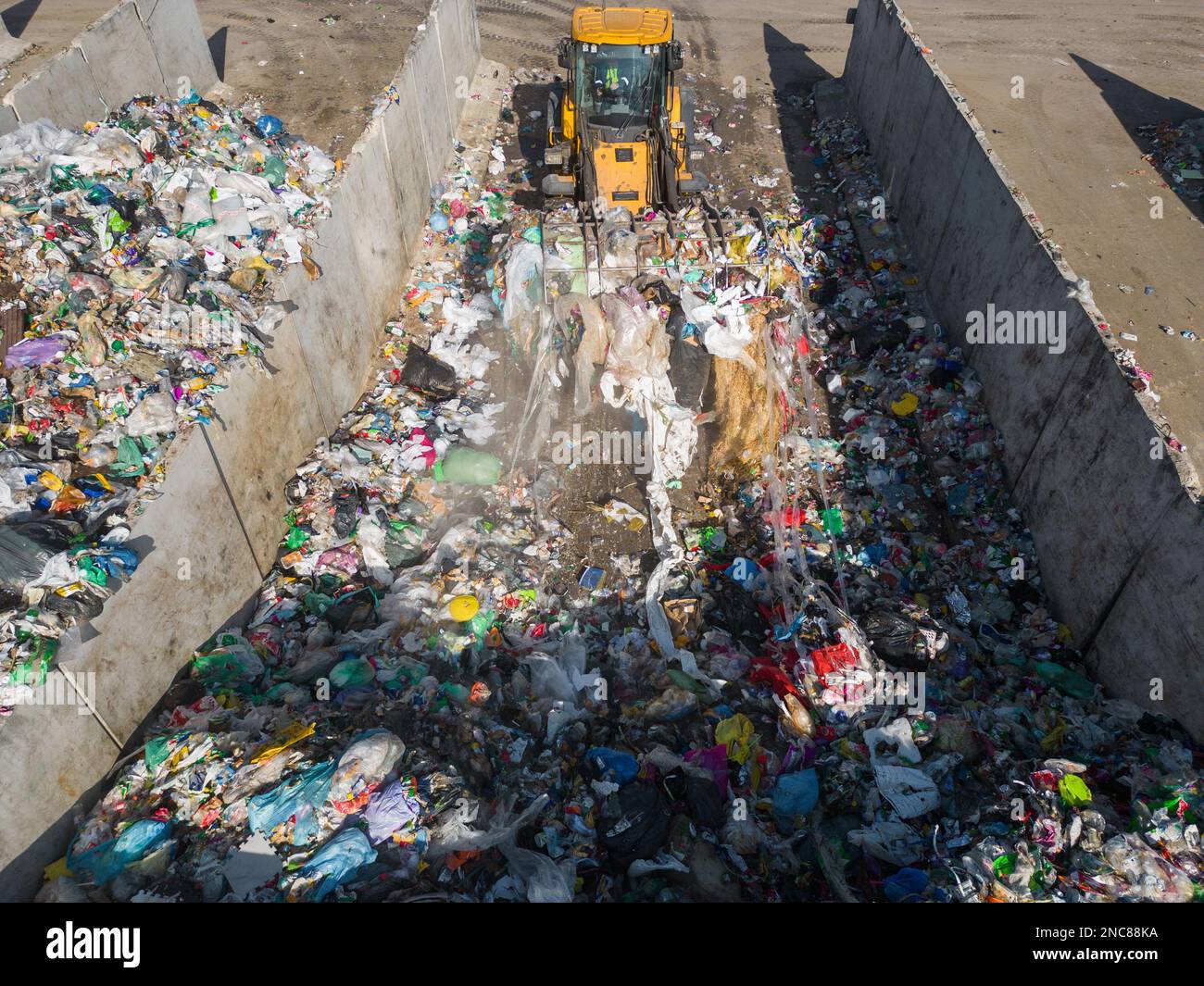 Wheeled loader operating on landfill site, carrying and dumping waste ...