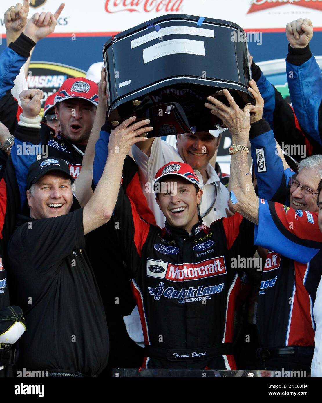 Trevor Bayne, center, holds up the trophy in Victory Lane with help ...