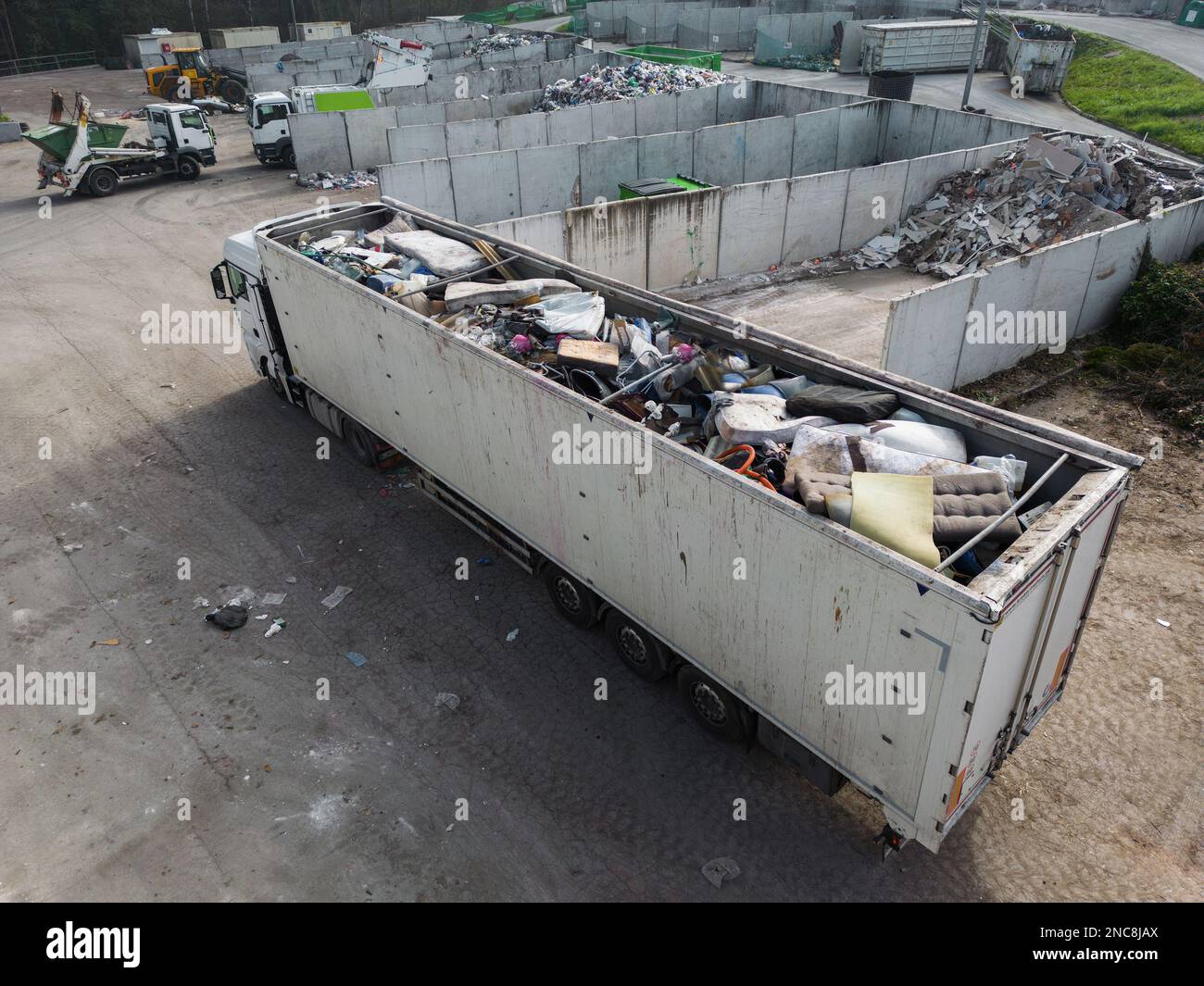 Recycling center truck full of household waste, parked near box areas ...