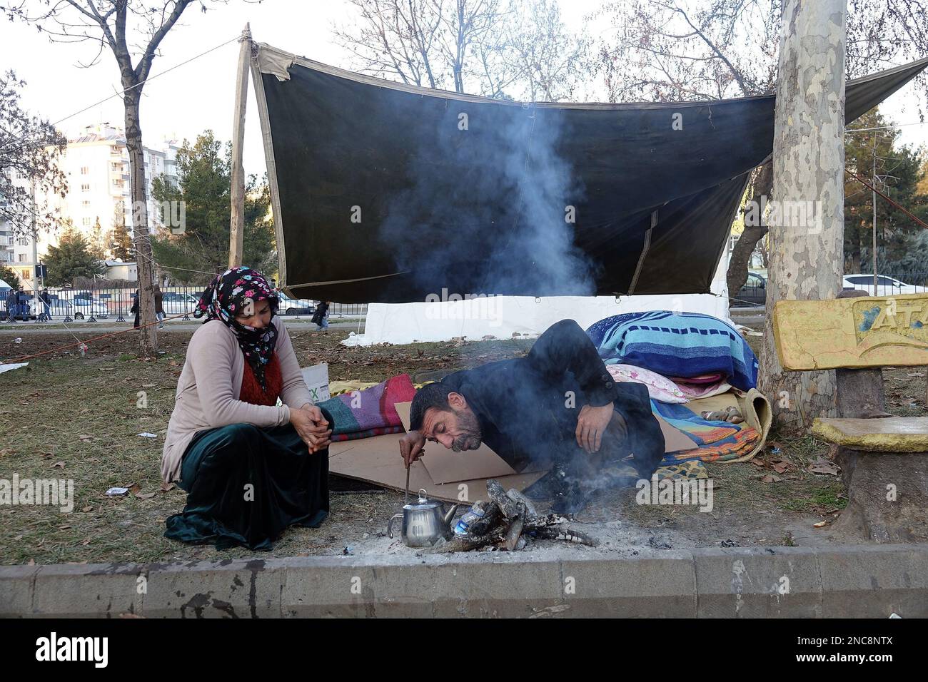A couple, makes fire to make tea near a primitive shack they built ...