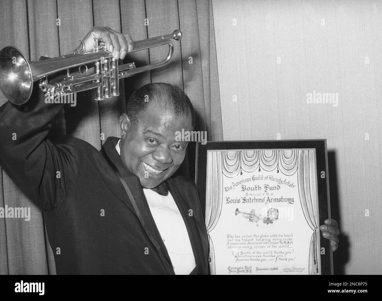 Louis Armstrong holds his trumpet in jubilation as he shows off his ...