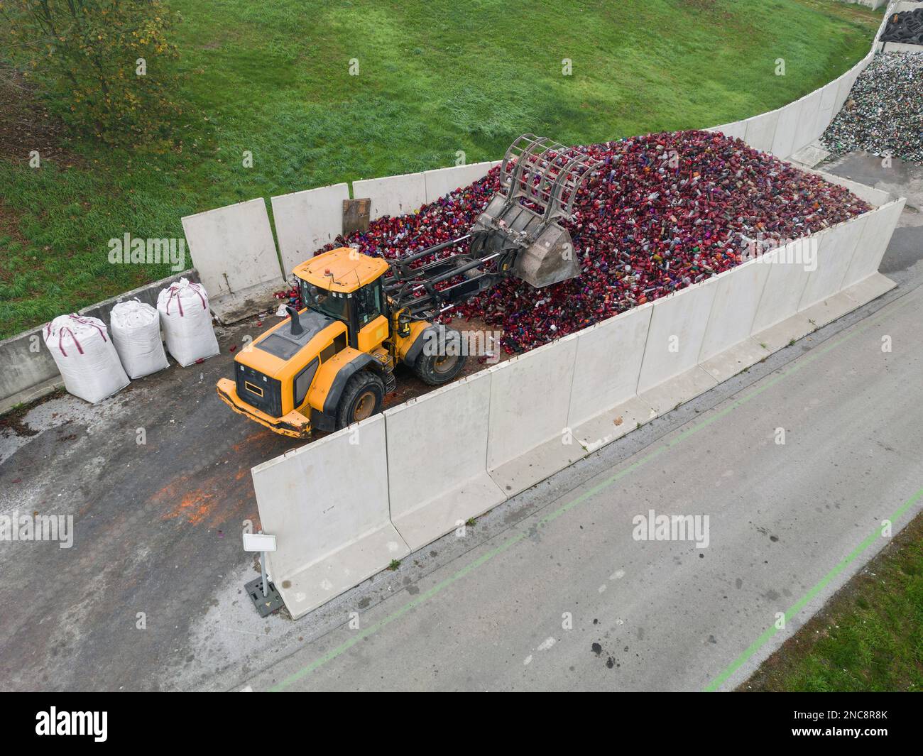 Yellow skid steer loader grabbing grave candle waste with scrap grapple ...