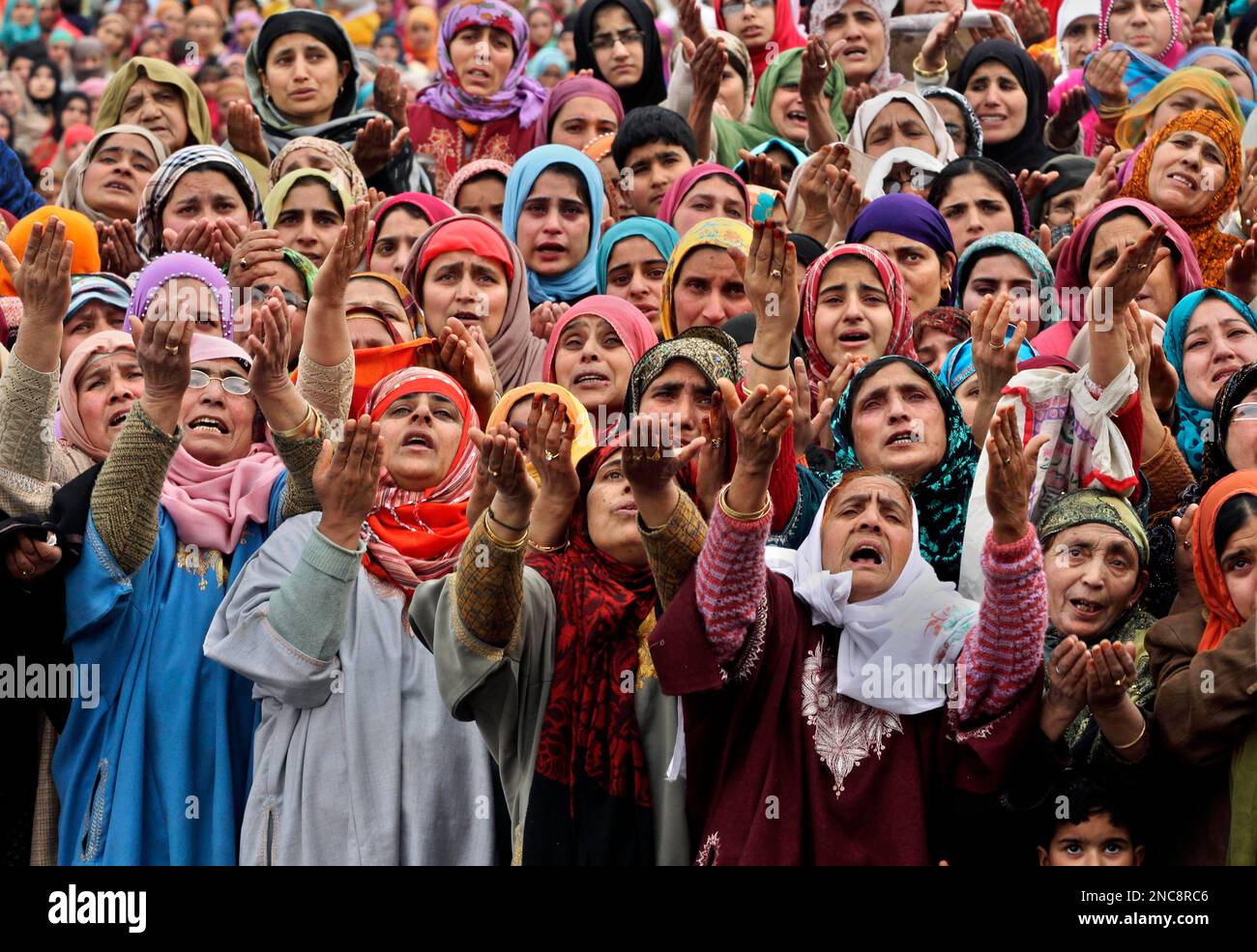 Kashmiri Muslim devotees raise their hands for prayers as a head priest ...