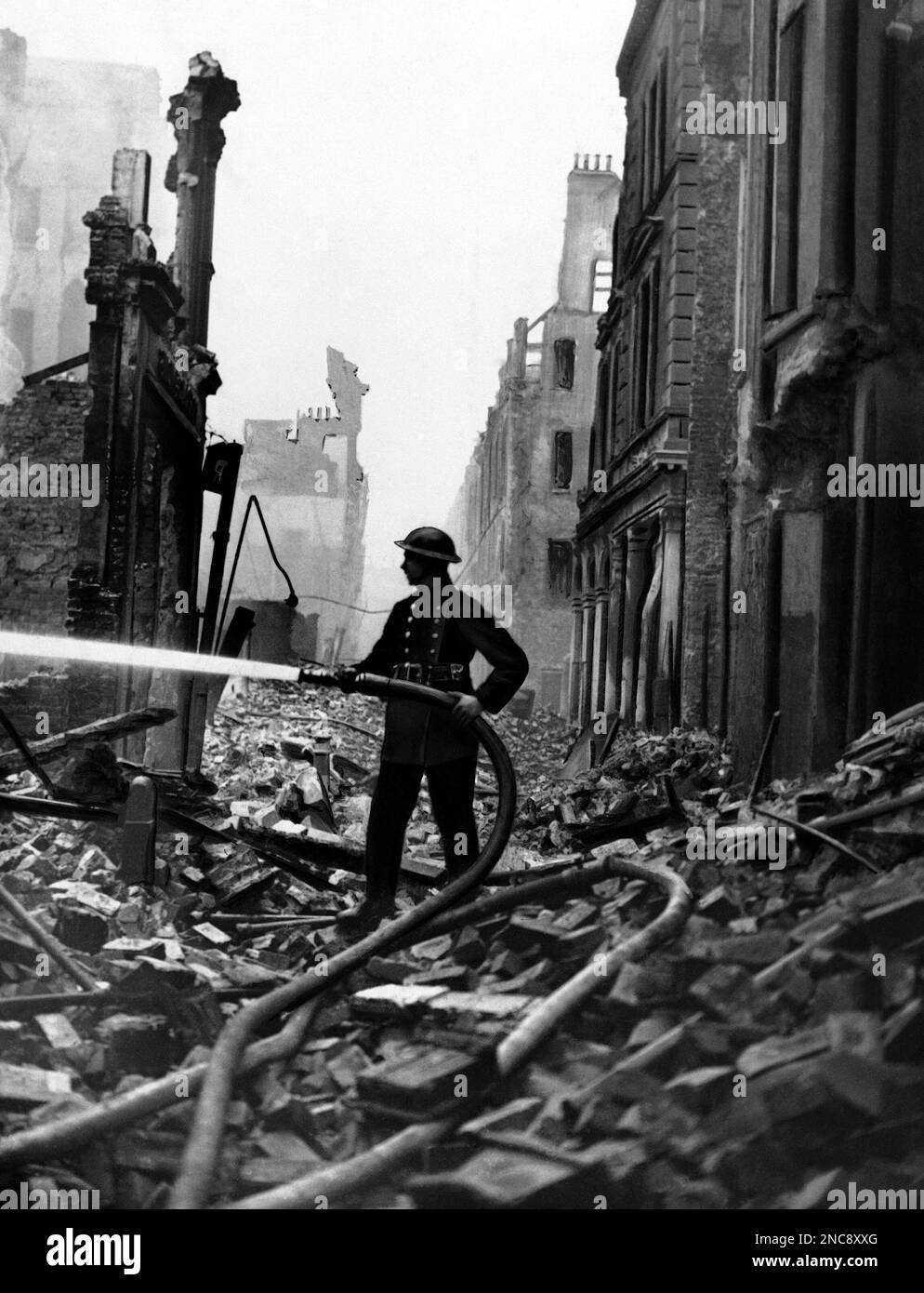 A British fireman of the ARP shown fighting a fire in the destruction ...