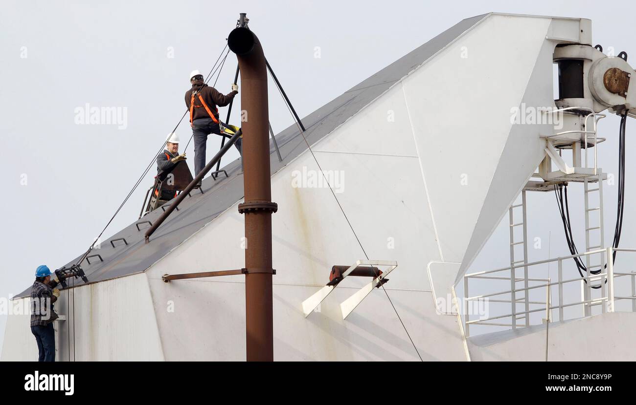 Three men work high atop the cargo ship Dorothy Ann of the Interlake ...