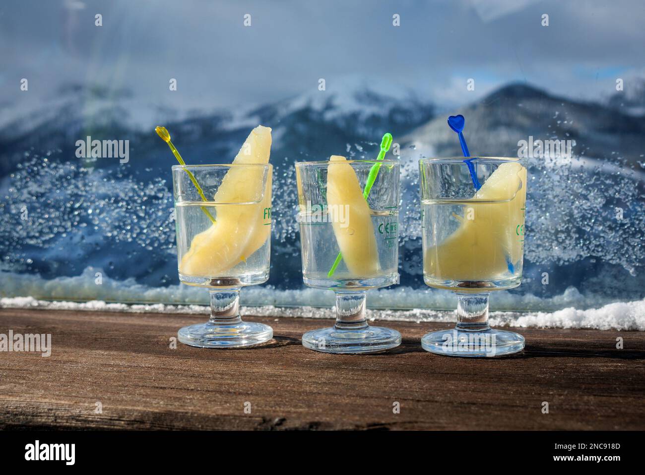 3 shot glasses filled with schnapps and a piece of pear stand in front ...