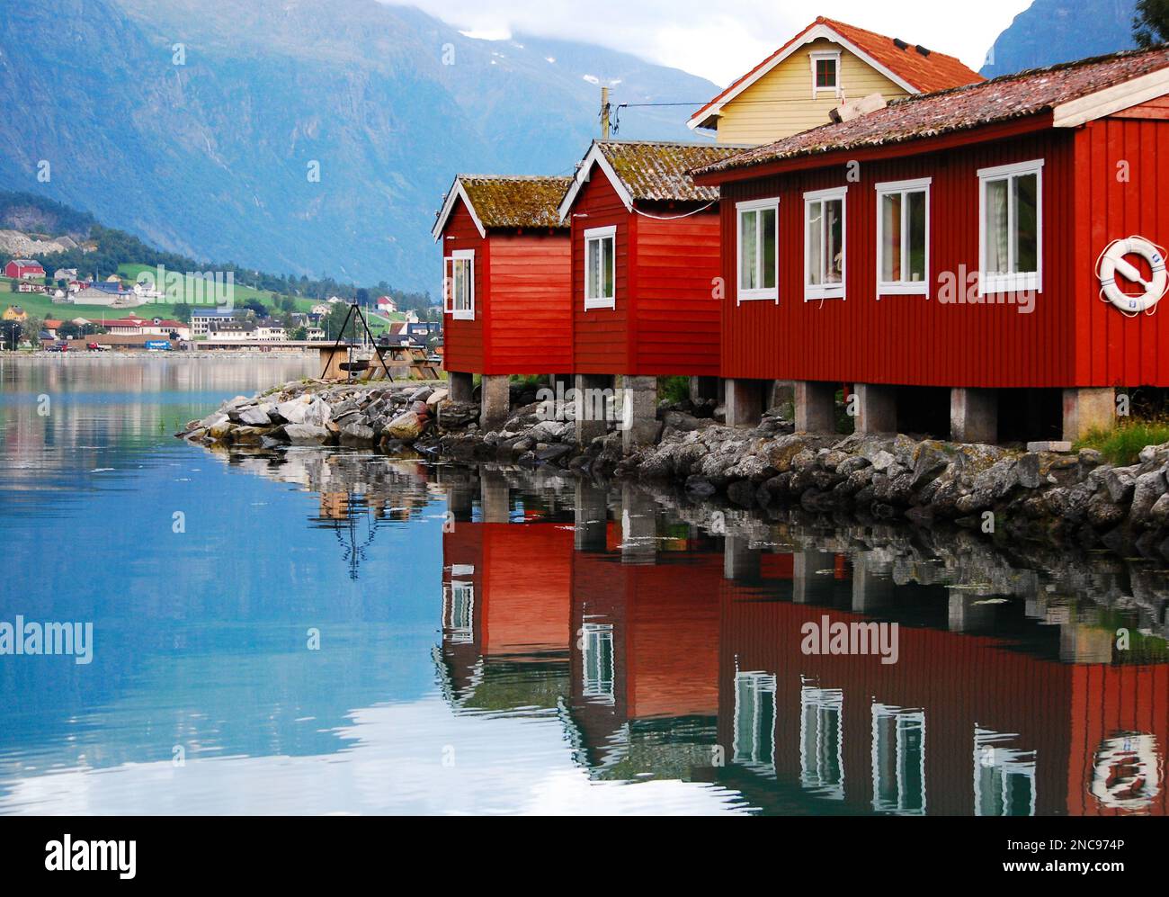 Traditional wooden red cottages on the shores of a fjord in Norway. In ...