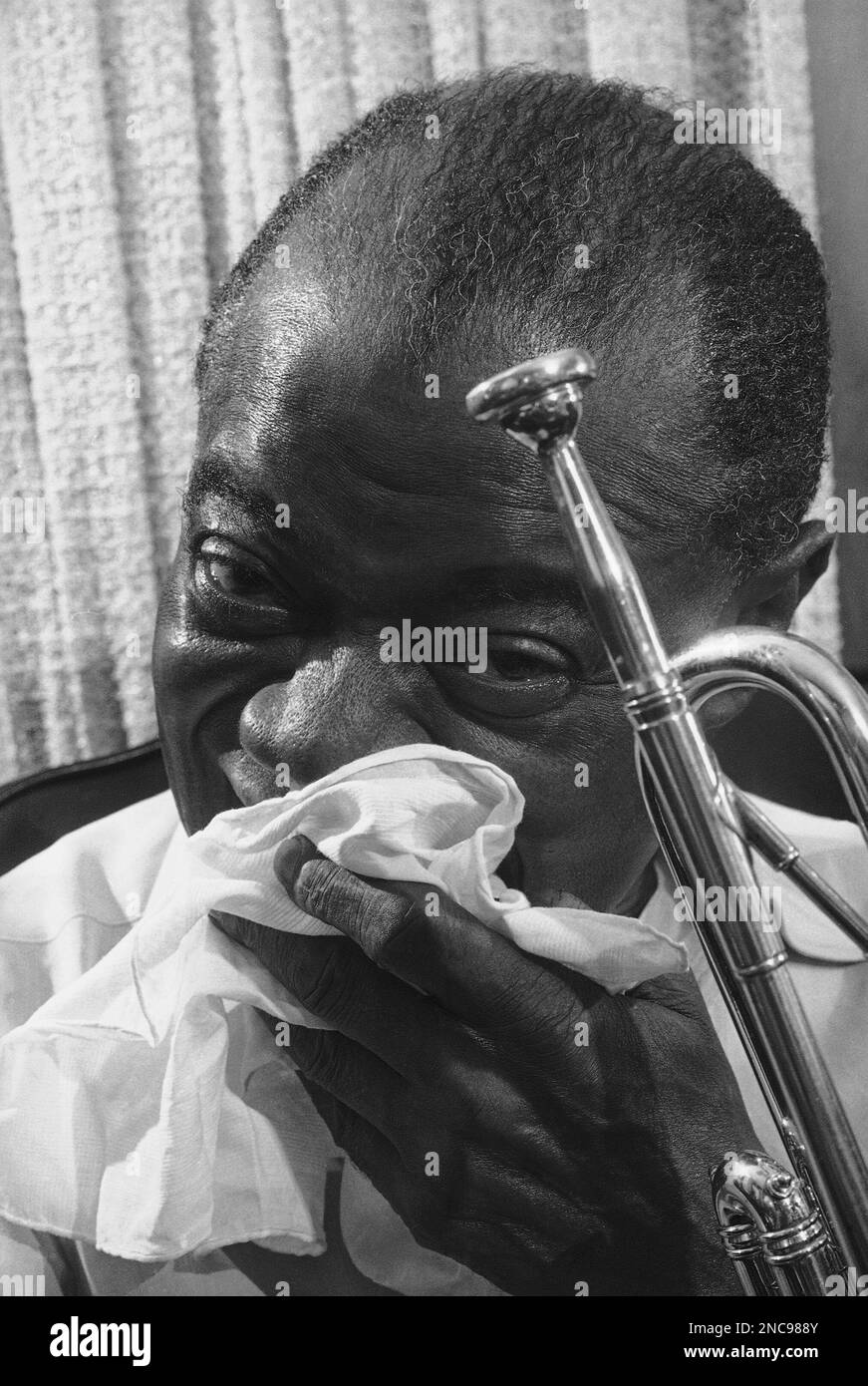 Louis “Satchmo” Armstrong, that great trumpeter of jazz, wipes his lips ...