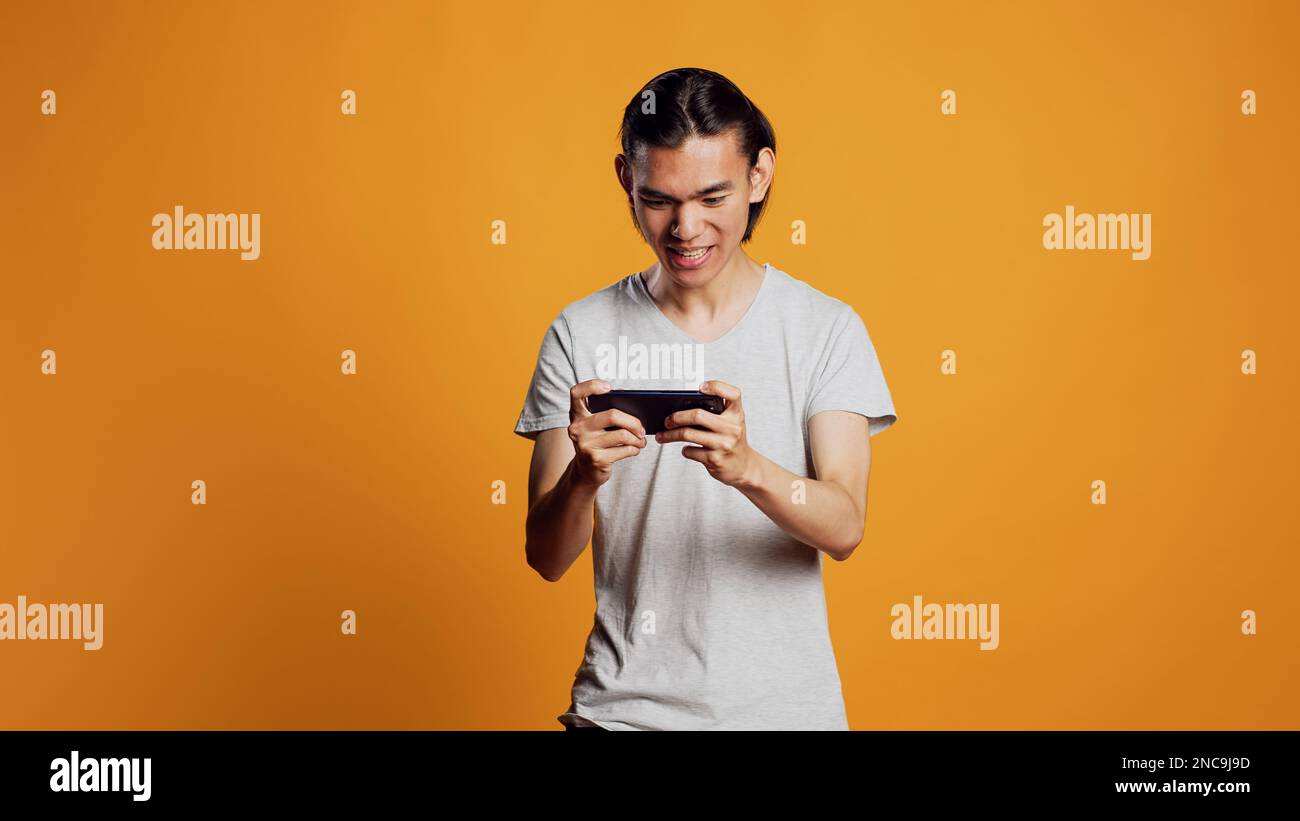 Happy male model playing video games on smartphone, using online gaming ...