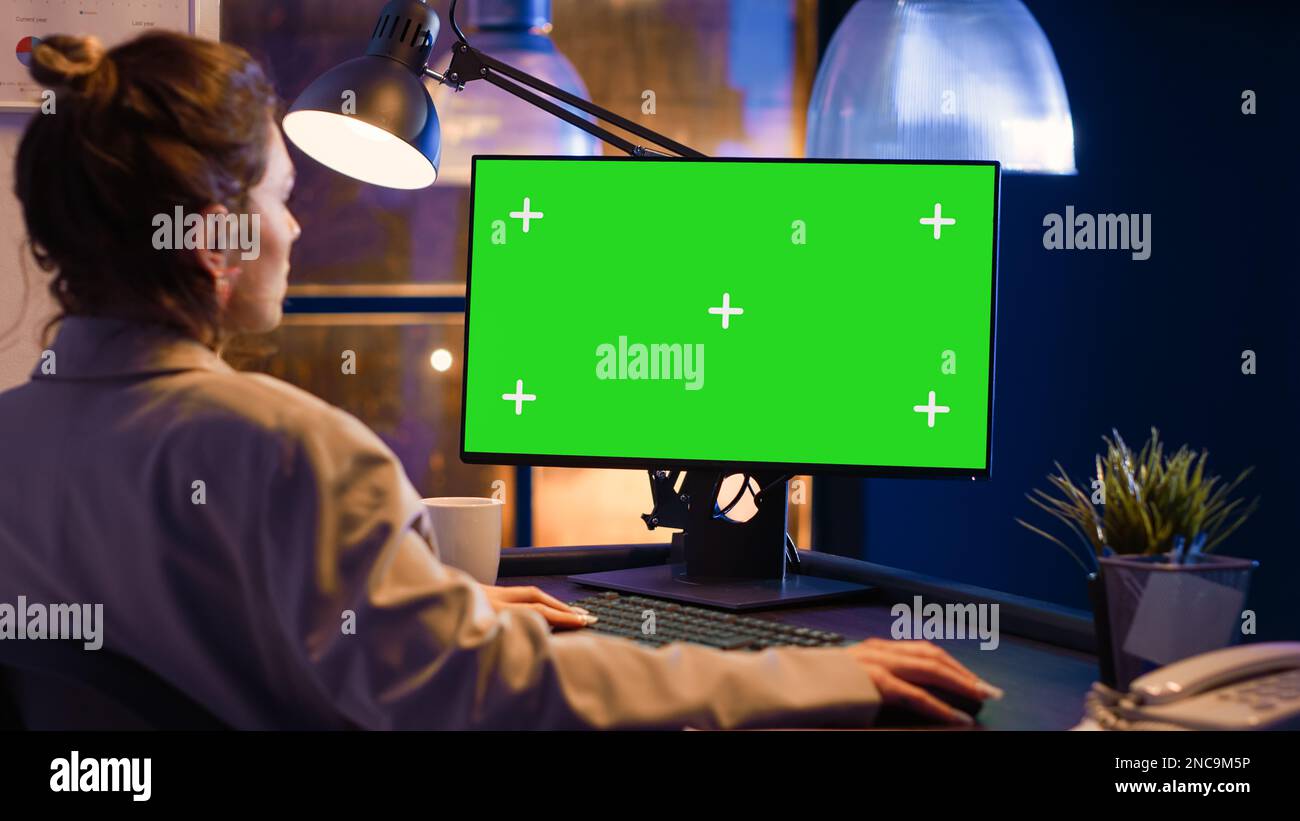 Business woman analyzing green screen display on pc, looking at computer with chroma key ...