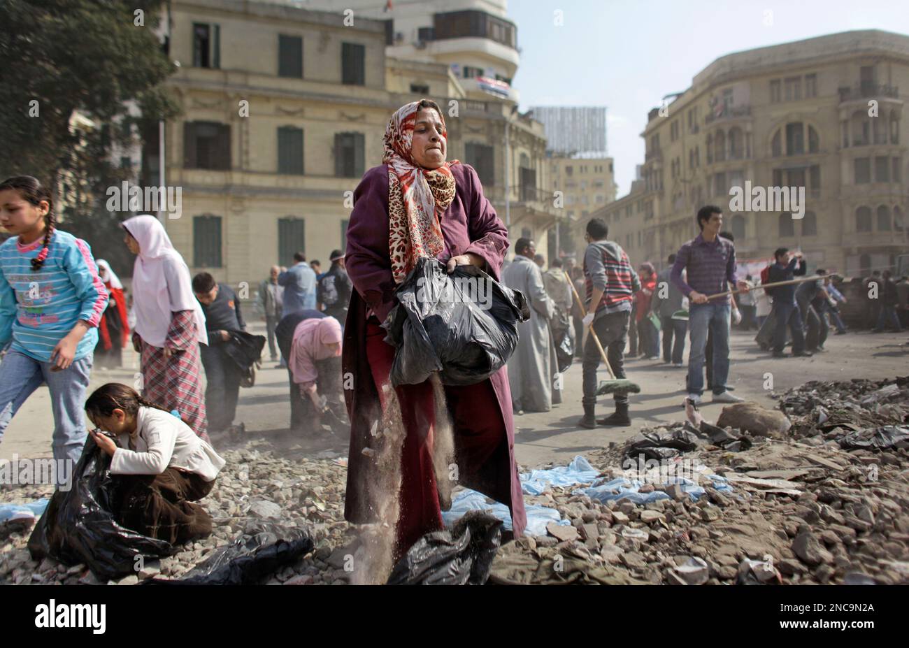 Egyptian volunteers clean up garbage and rocks from the street outside ...