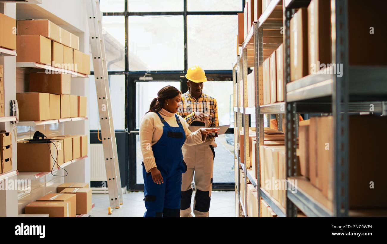 Group of people using laptop in warehouse space, man and woman checking ...