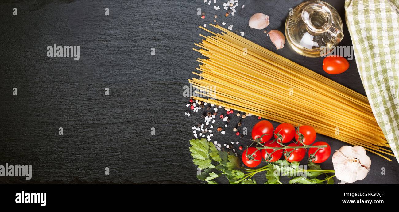 Pasta, spaghetti and cooking ingridients on black slate surface ...