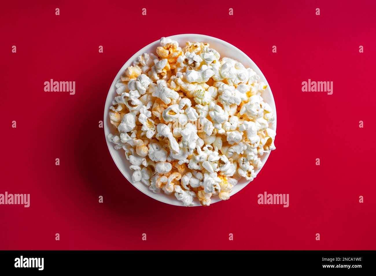 Tasty cheese popcorn in bowl isolated on red background. Top view, flat ...