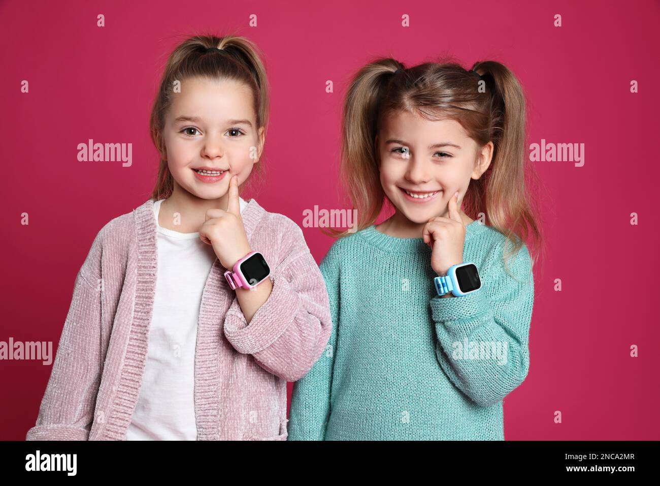 Little girls with smart watches on pink background Stock Photo - Alamy